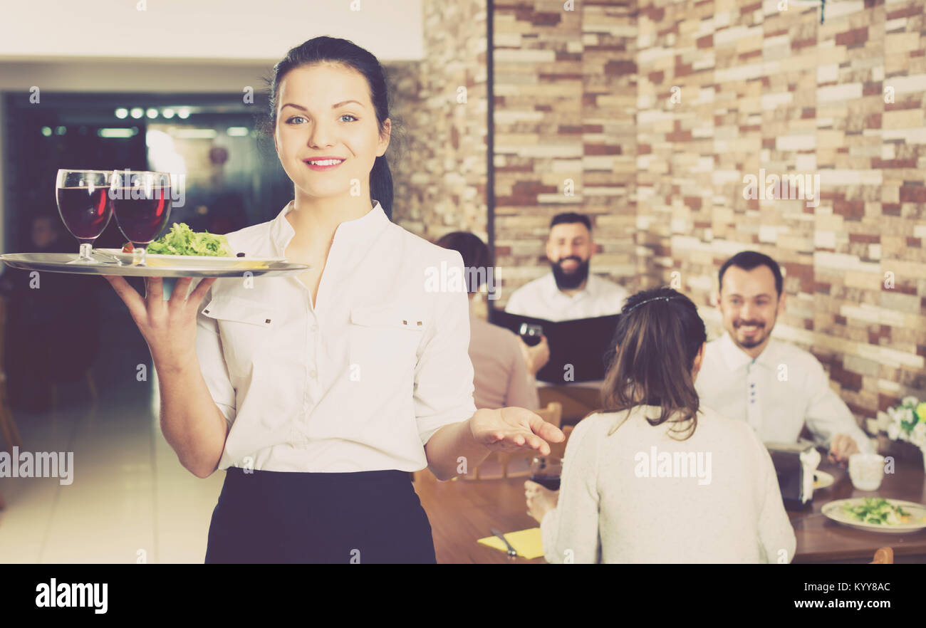 Smiling female waiter greeting customers at table in restaurant Stock ...