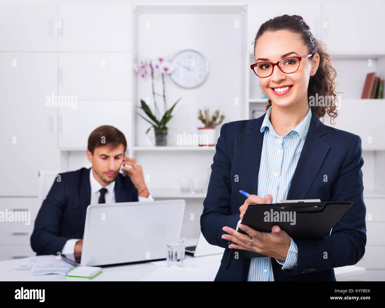 Smiling efficient business female secretary having cardboard in hands ...