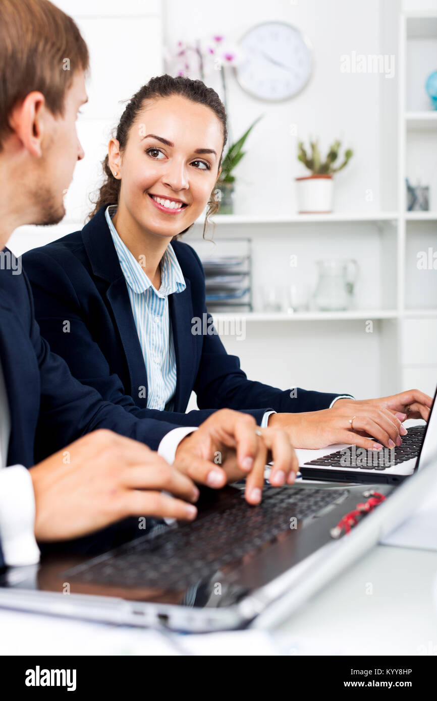 Young man and positive woman coworkers sitting and working on computers ...
