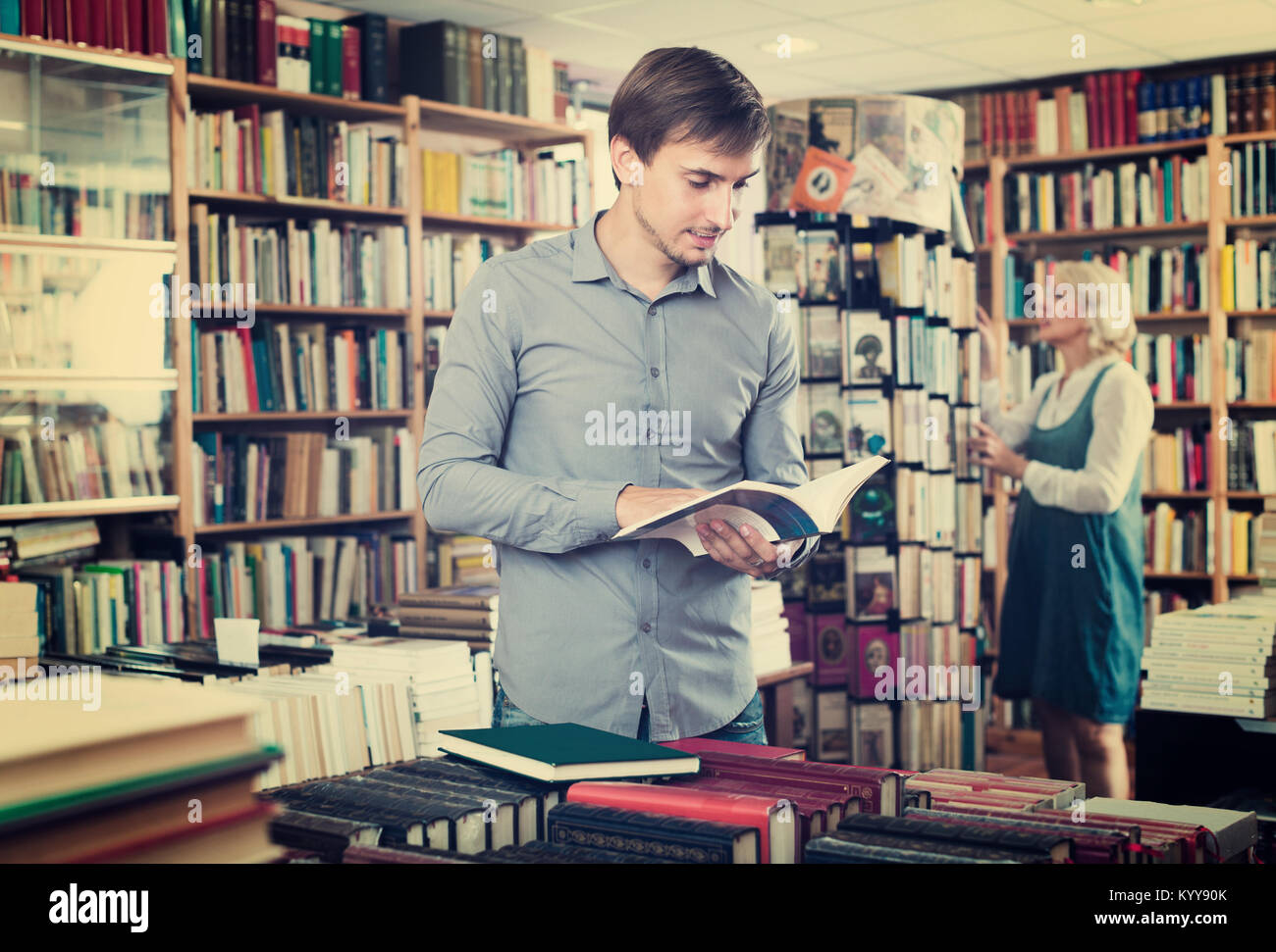 Man holding open book in hands and looking at it in book store Stock ...