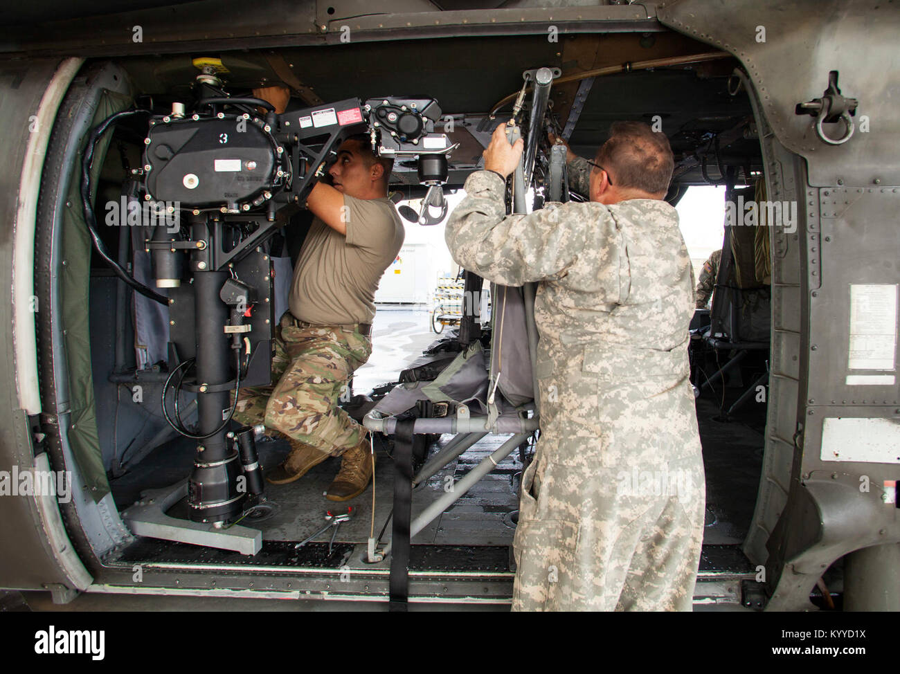 Army Spc. Pedro Nevarez, a UH-60 Black Hawk mechanic, left, installs a ...