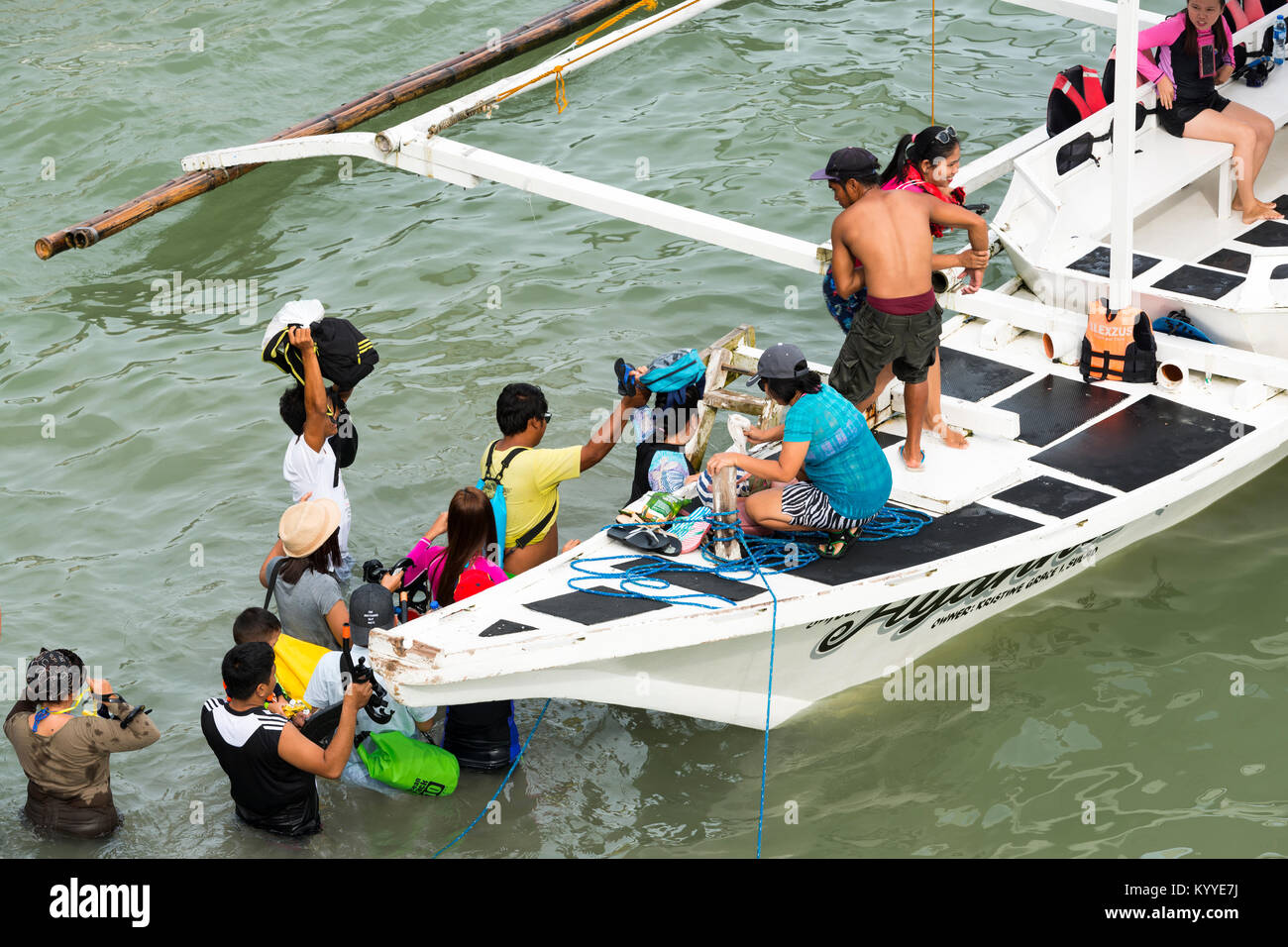 Double-outrigger boats loading tourists in the harbour of El Nido ...