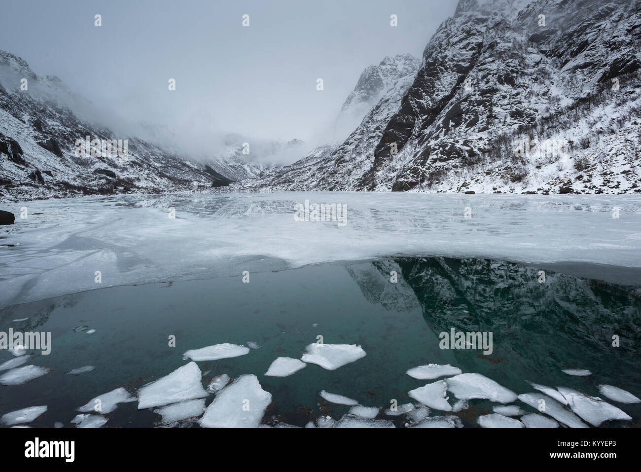 Reflection of mountains with ice floe floating on water, Lofoten ...