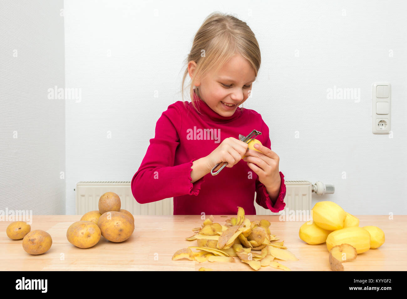A girl is wearing a red turtleneck sweater. He enjoys peeling potatoes ...