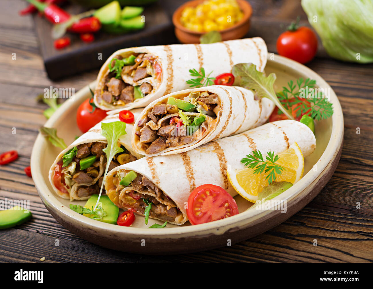 Burritos wraps with beef and vegetables on a wooden background. Beef ...
