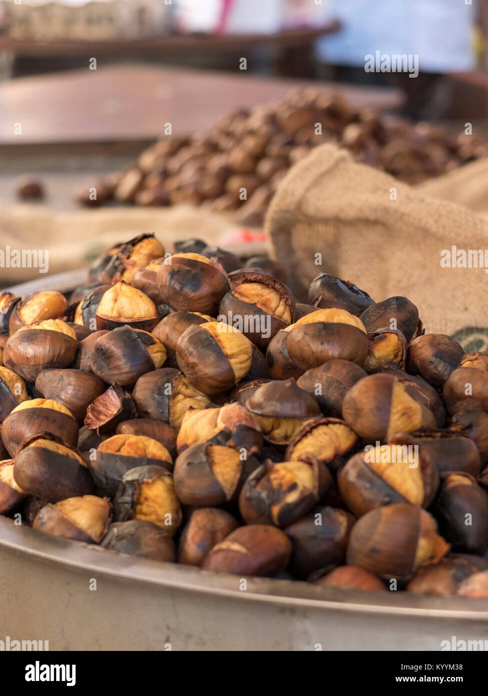 Roasted chestnuts cooked on a bin with wood fire. Near jute bags for ...
