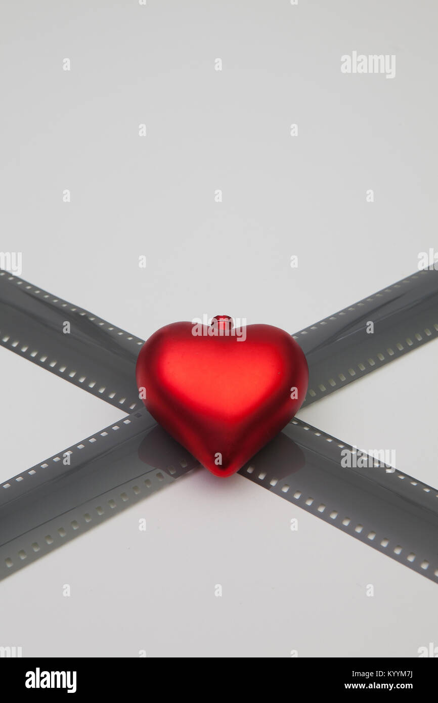 The red heart and the unrolled exposed 35mm film strips over a white ...