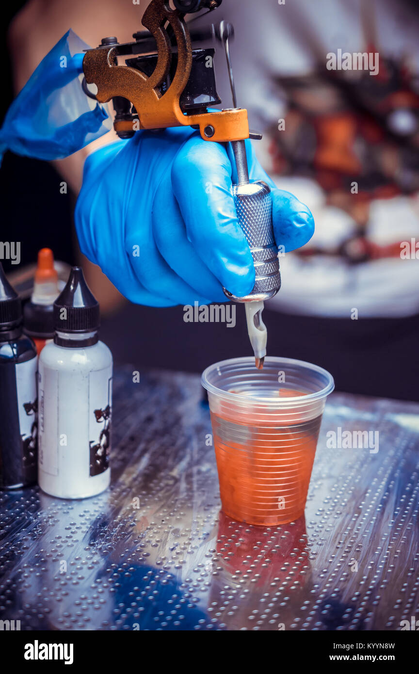 Hand of a tattooer, holding a tattoo machine Stock Photo - Alamy