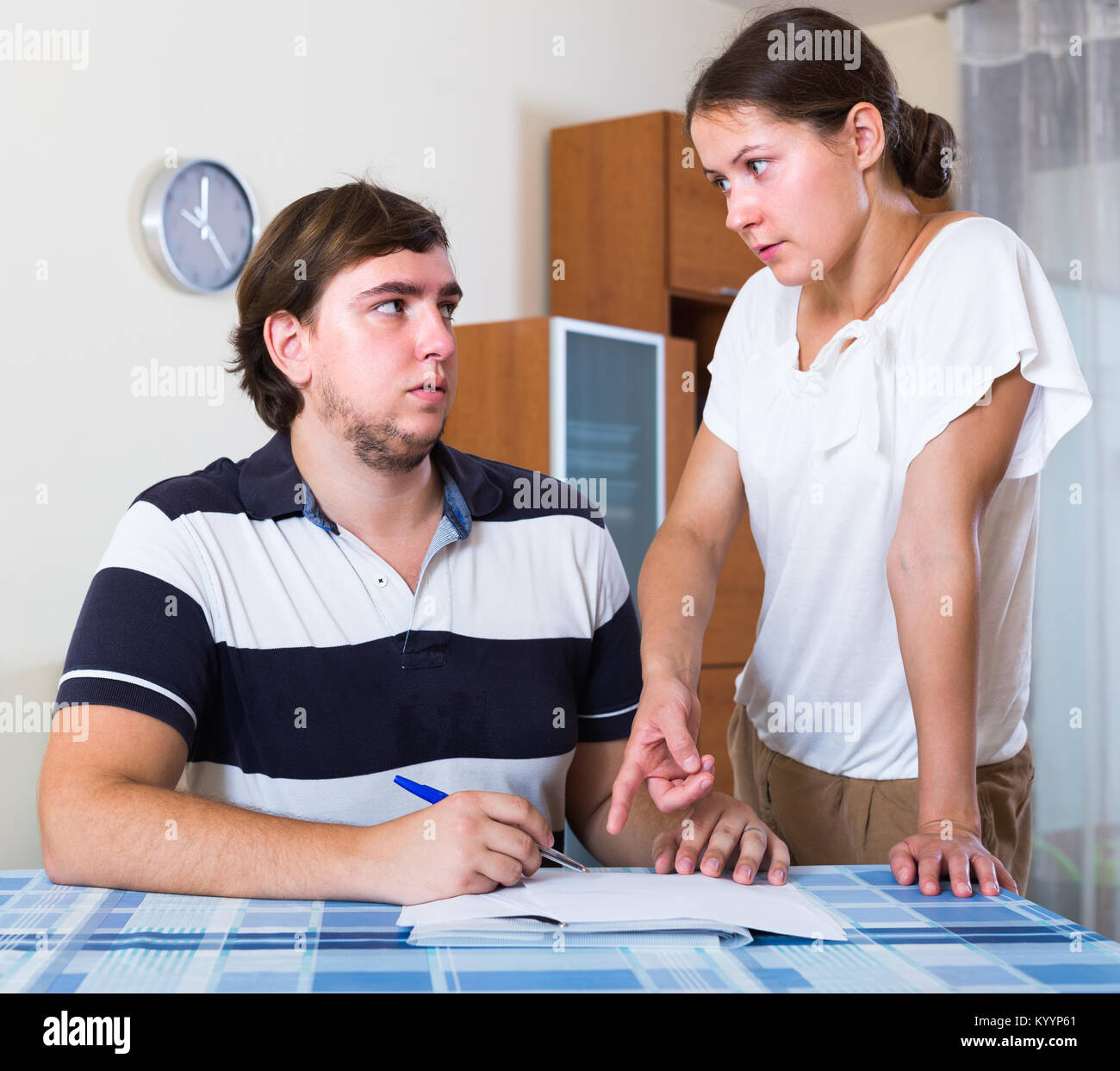 Serious couple sitting at desk with documents and counting budget Stock ...