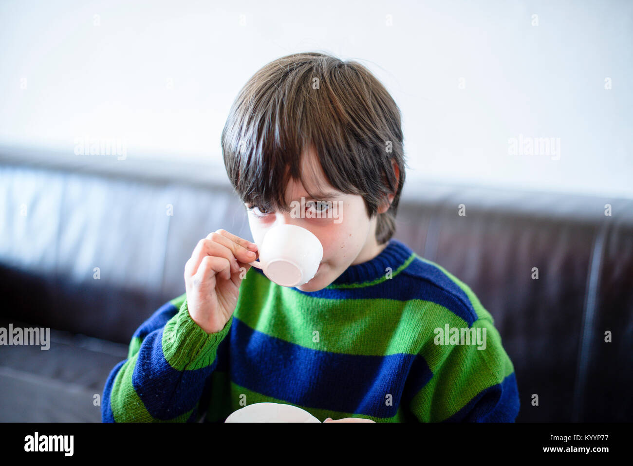 child plays, drinking tea on the sofa at home, lit by the window Stock ...