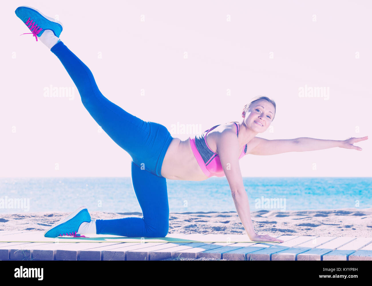 Positive healthy female stretching muscles on the sand Stock Photo - Alamy
