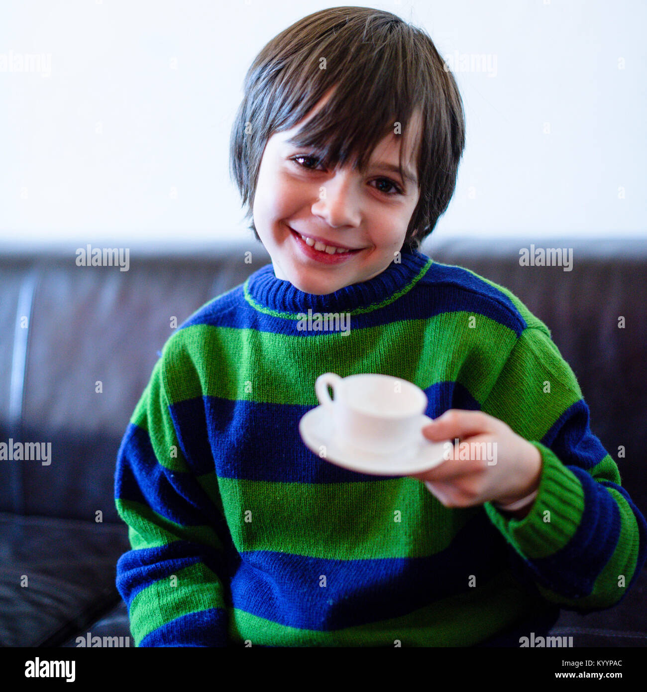 child plays, drinking tea on the sofa at home, lit by the window Stock ...