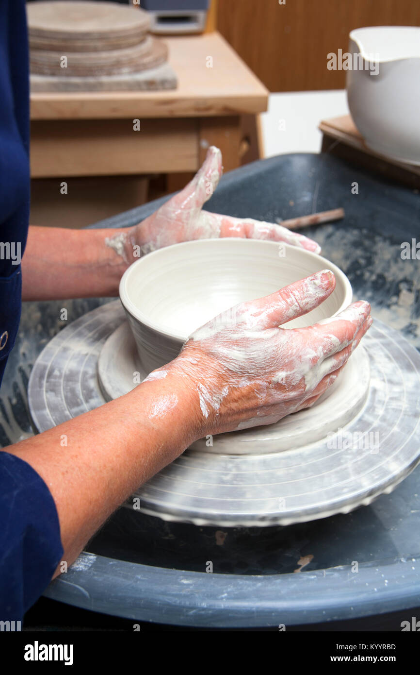 A lady ceramics artist at work in her home pottery studio, throwing a ...
