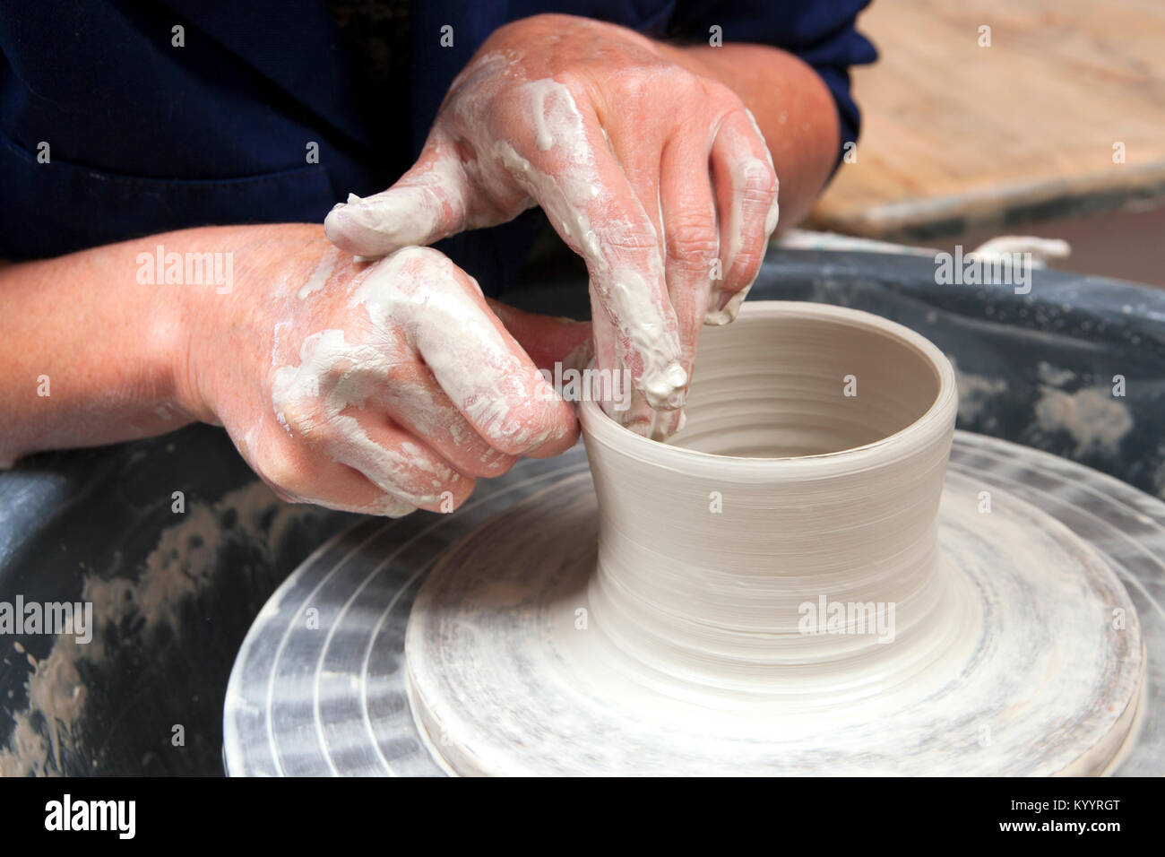 A lady ceramics artist at work in her home pottery studio, forming a ...
