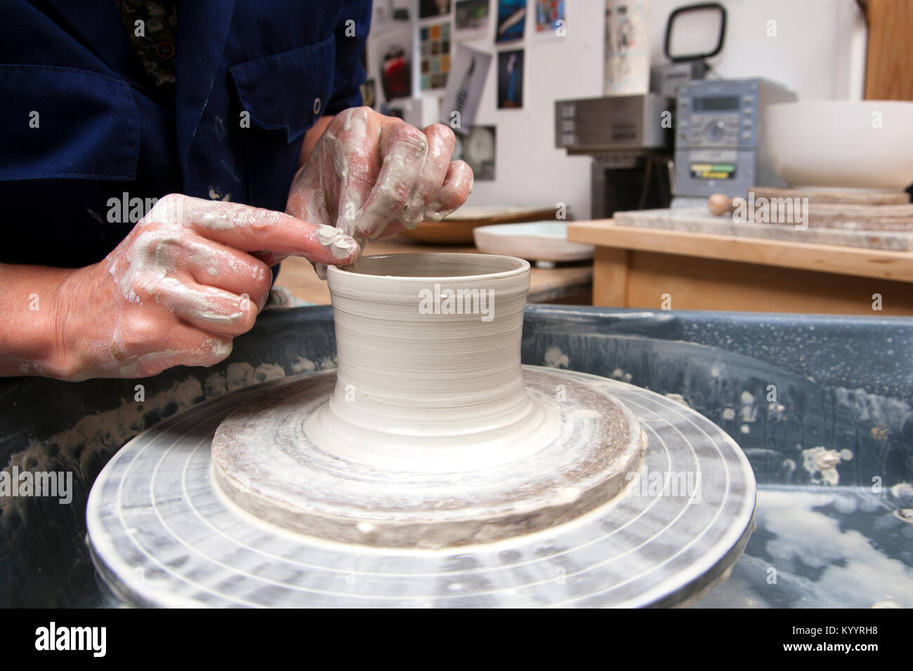 A lady ceramics artist at work in her home pottery studio, forming a ...