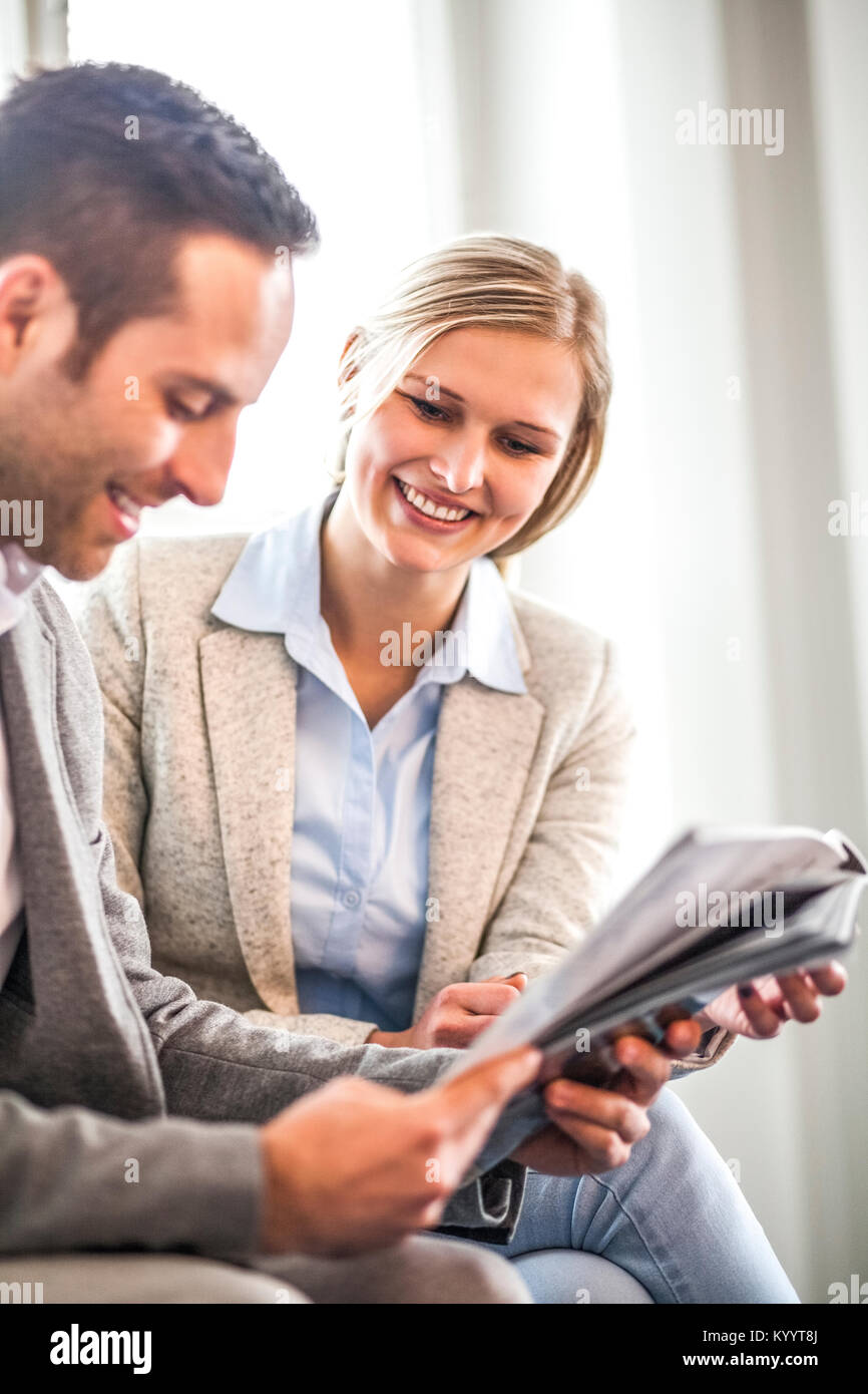 Smiling young business people reading brochure in office Stock Photo ...