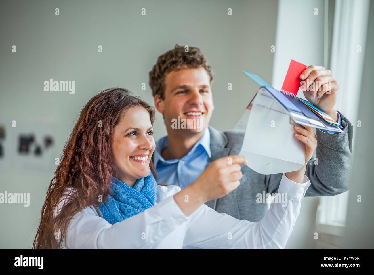 Smiling young business people choosing red color from swatches in ...