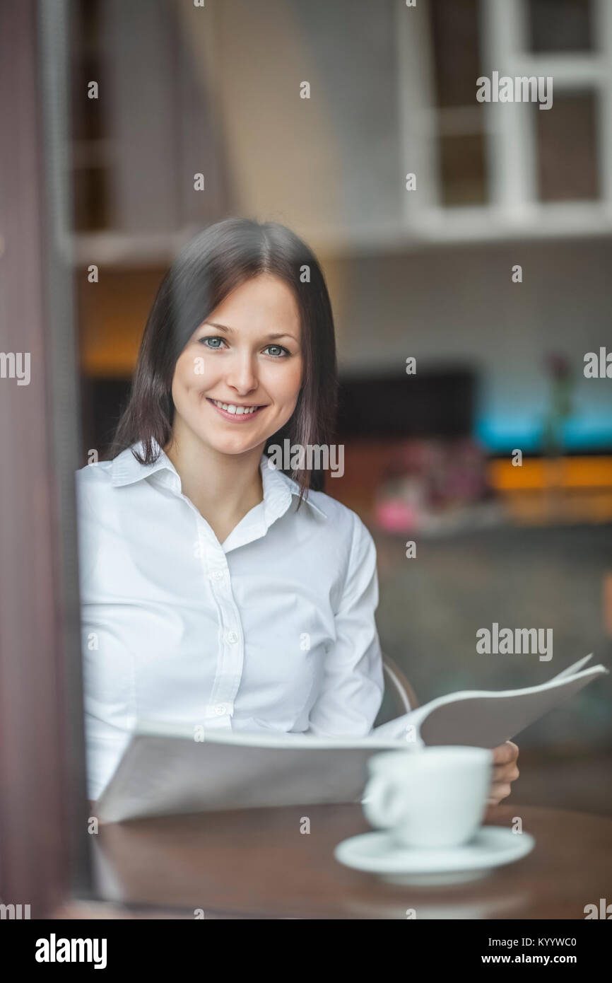 Portrait of beautiful young businesswoman reading book in coffee shop ...
