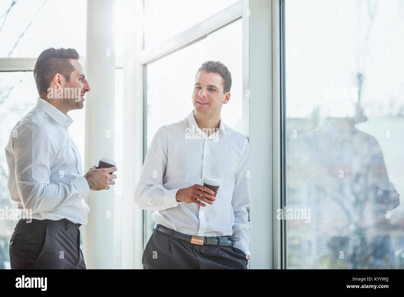 Standing talking holding cups hi-res stock photography and images - Alamy