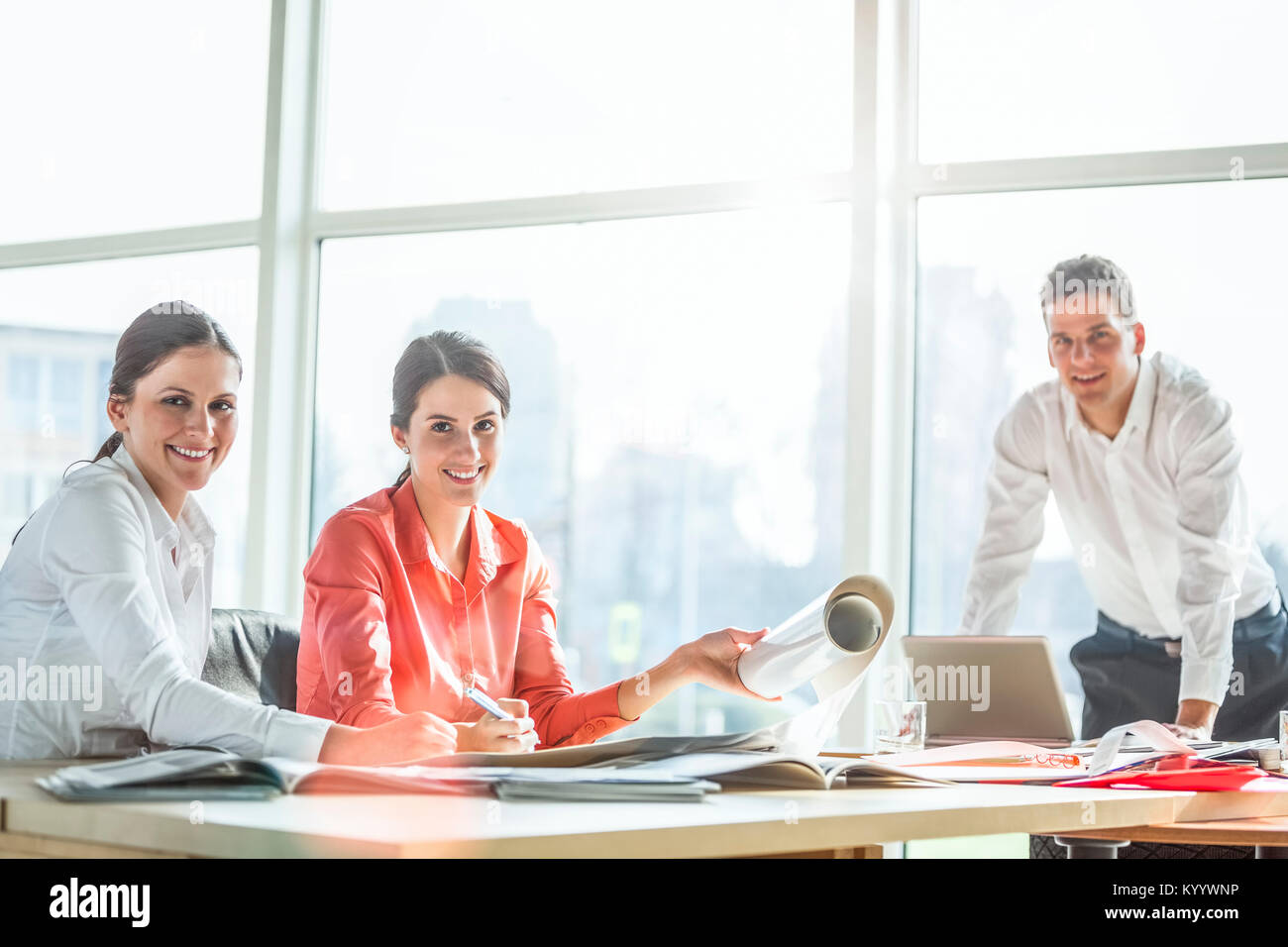 Portrait of confident young architects working on blueprint at desk in ...