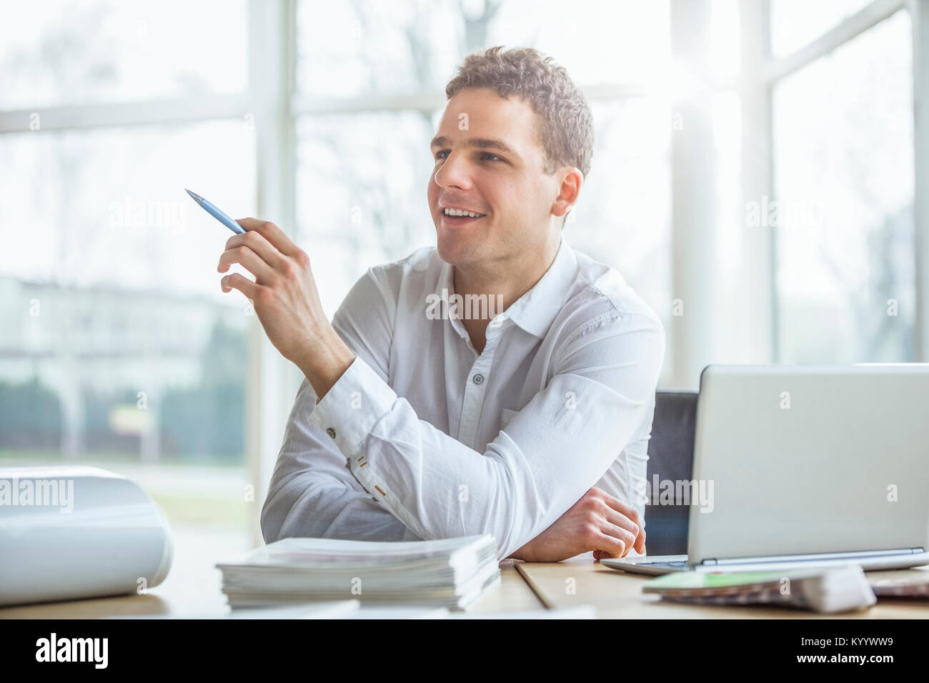 Portrait of handsome young businessman using laptop at office desk ...
