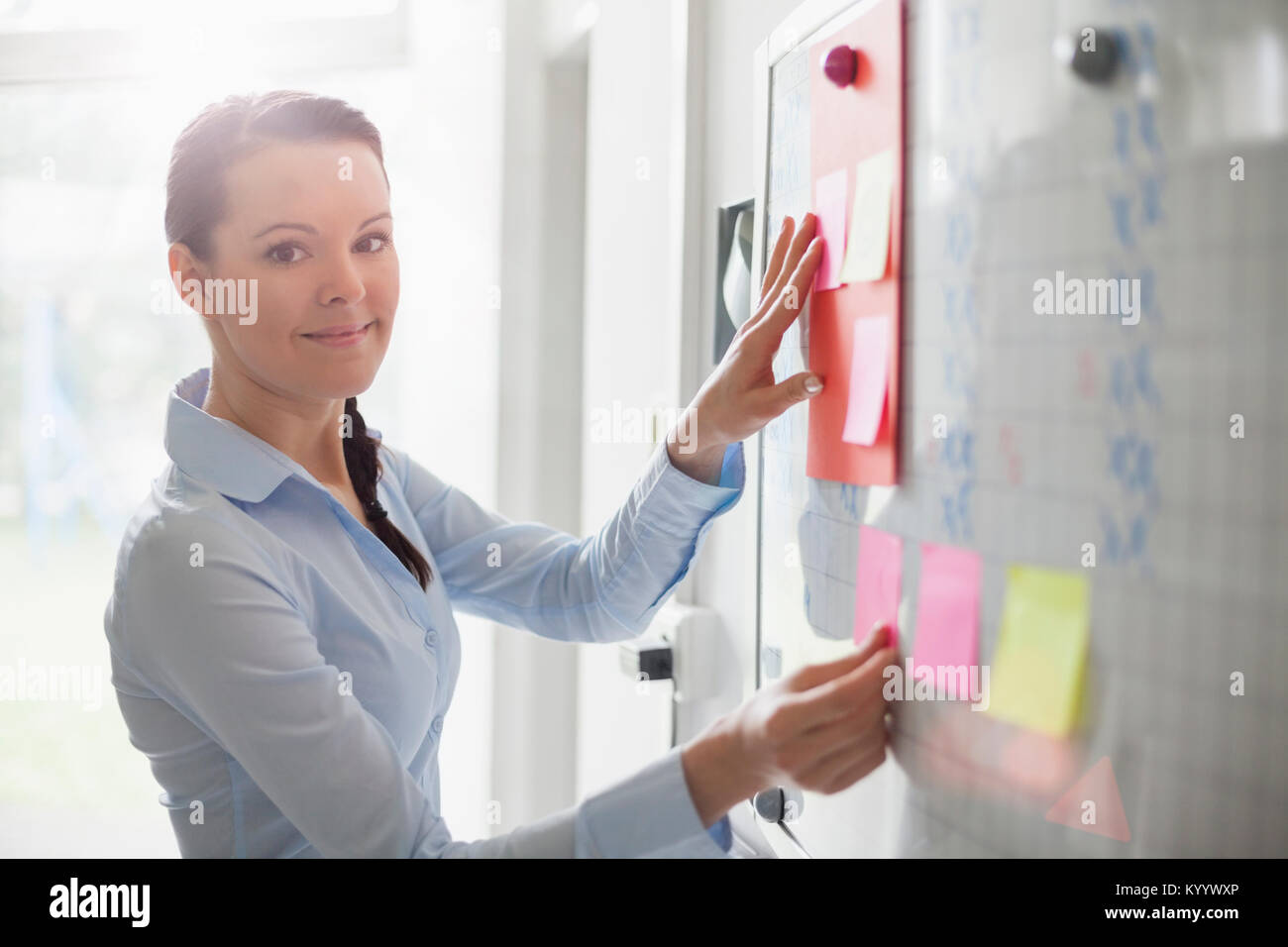 Portrait of beautiful young businesswoman reviewing sticky notes in ...