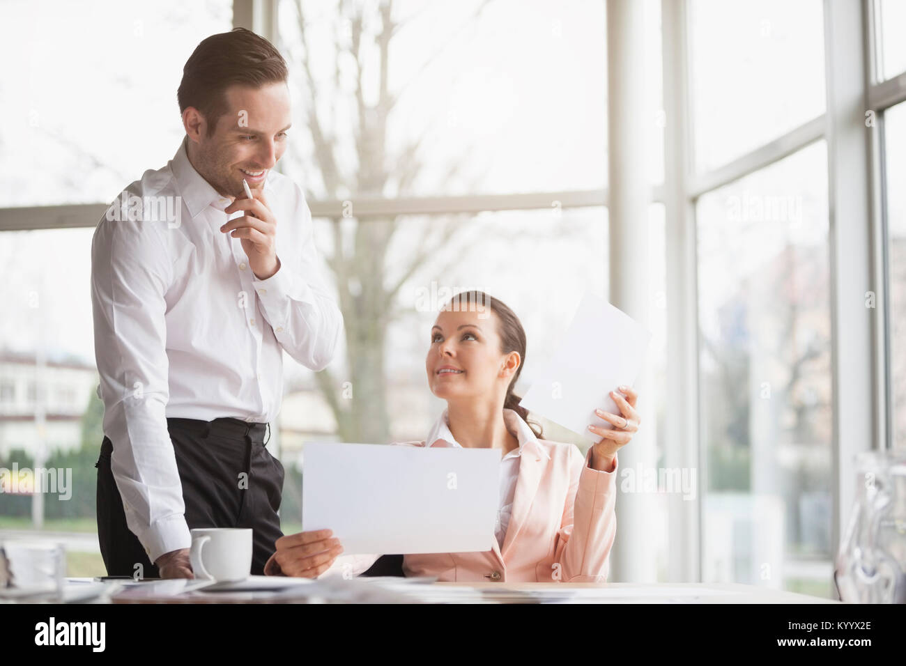 Young business people with paperwork at desk in office Stock Photo - Alamy