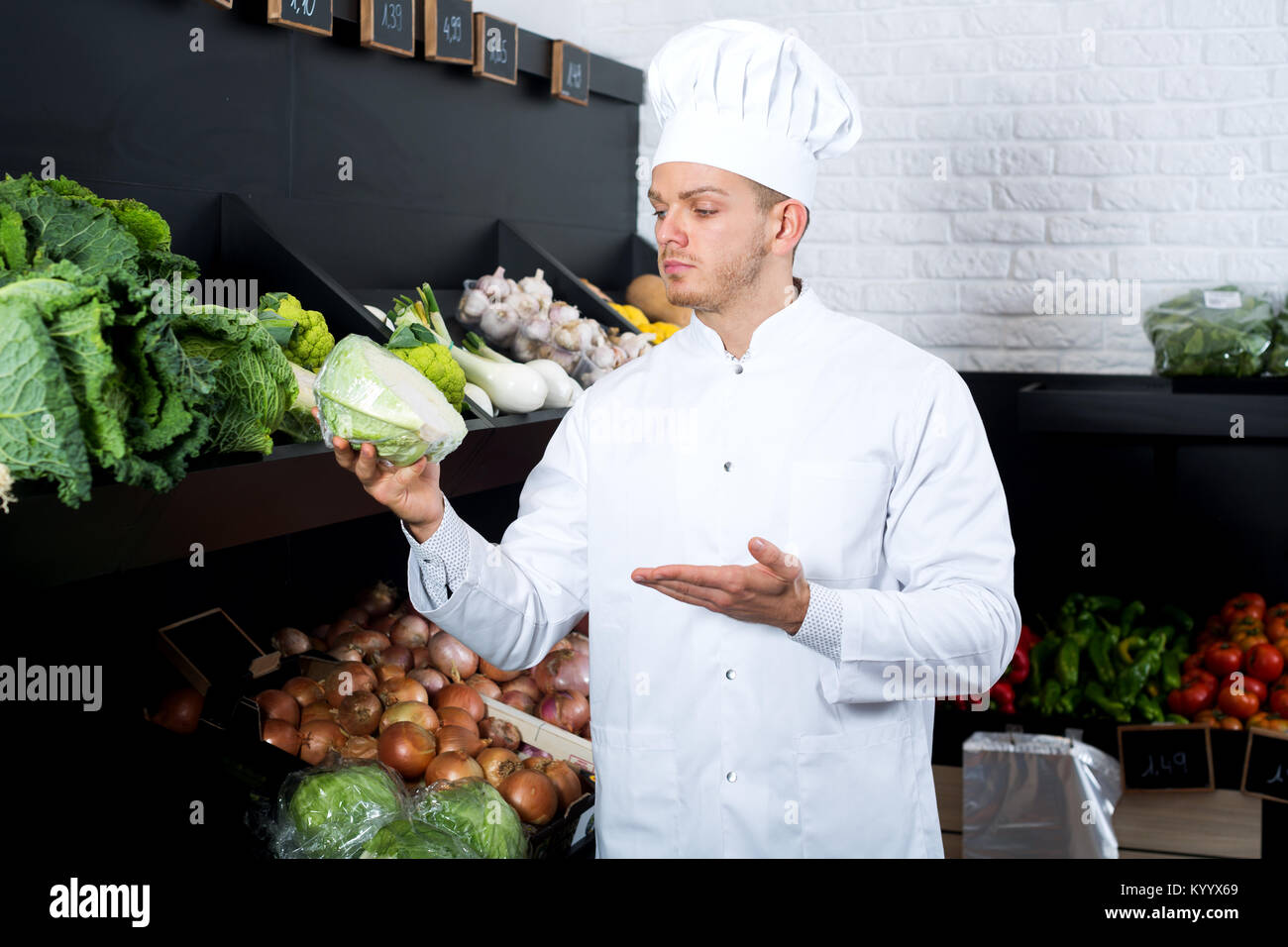 Positive man cook deciding on best vegetables in grocery shop Stock ...