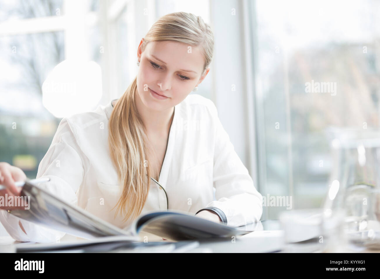 Young businesswoman reading brochure in office Stock Photo - Alamy