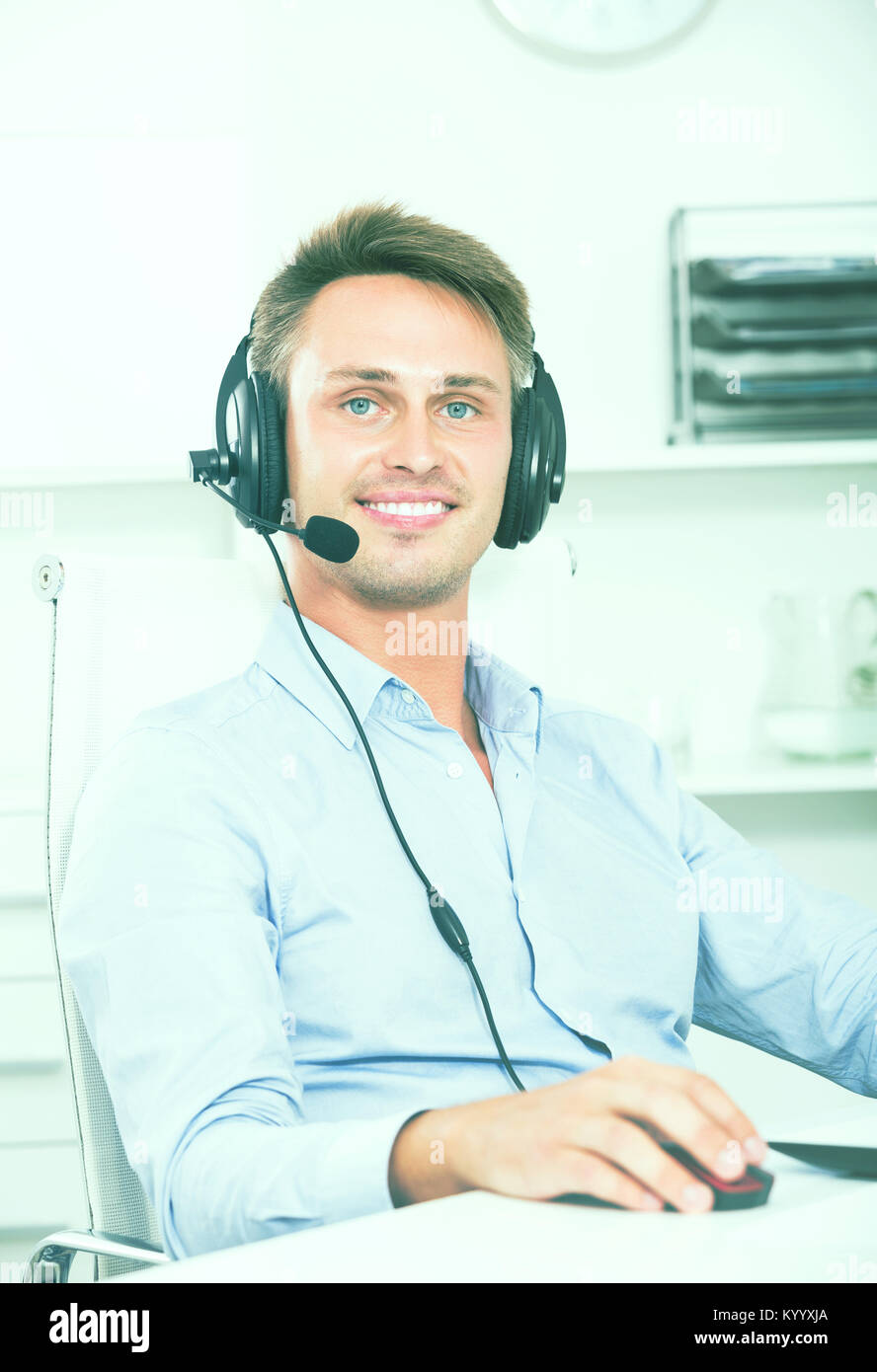 Portrait of young male operator with headset on answering at call ...