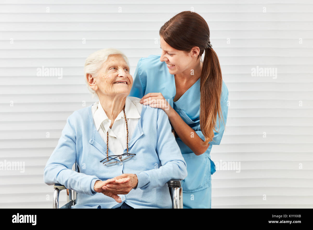 Smiling senior citizen in wheelchair and nurse at the elderly care in ...