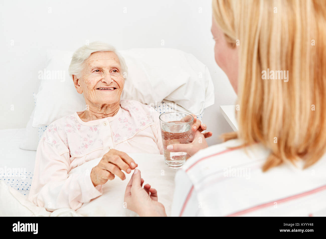 Sick elderly woman lies in bed and takes a medicine with water Stock ...