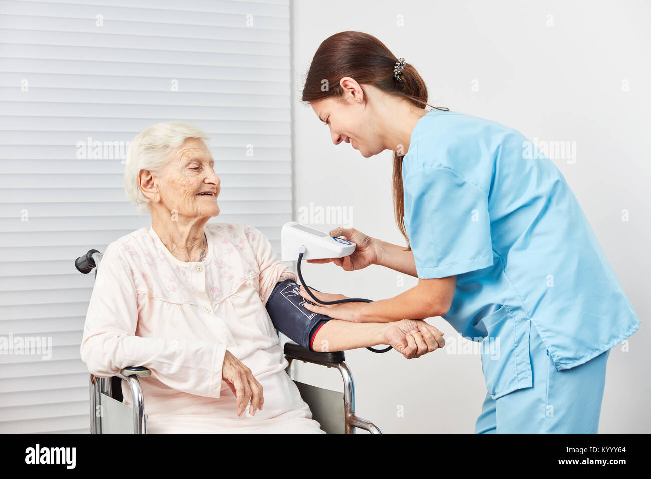 Nurse or caregiver makes blood pressure measurement in old patient ...