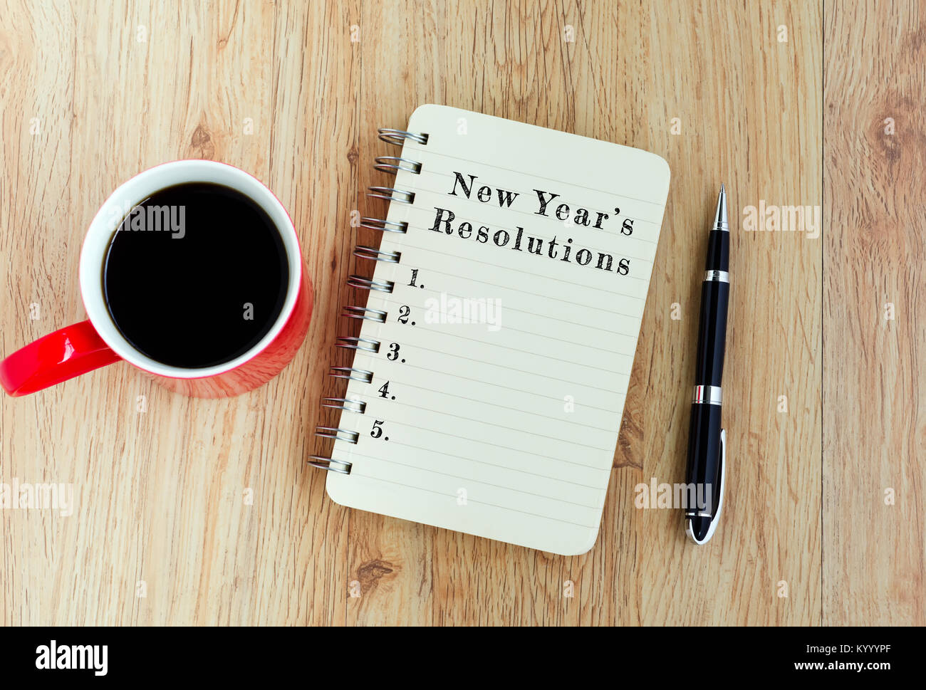 New Year's Resolutions text on notepad with pen and a cup of coffee ...