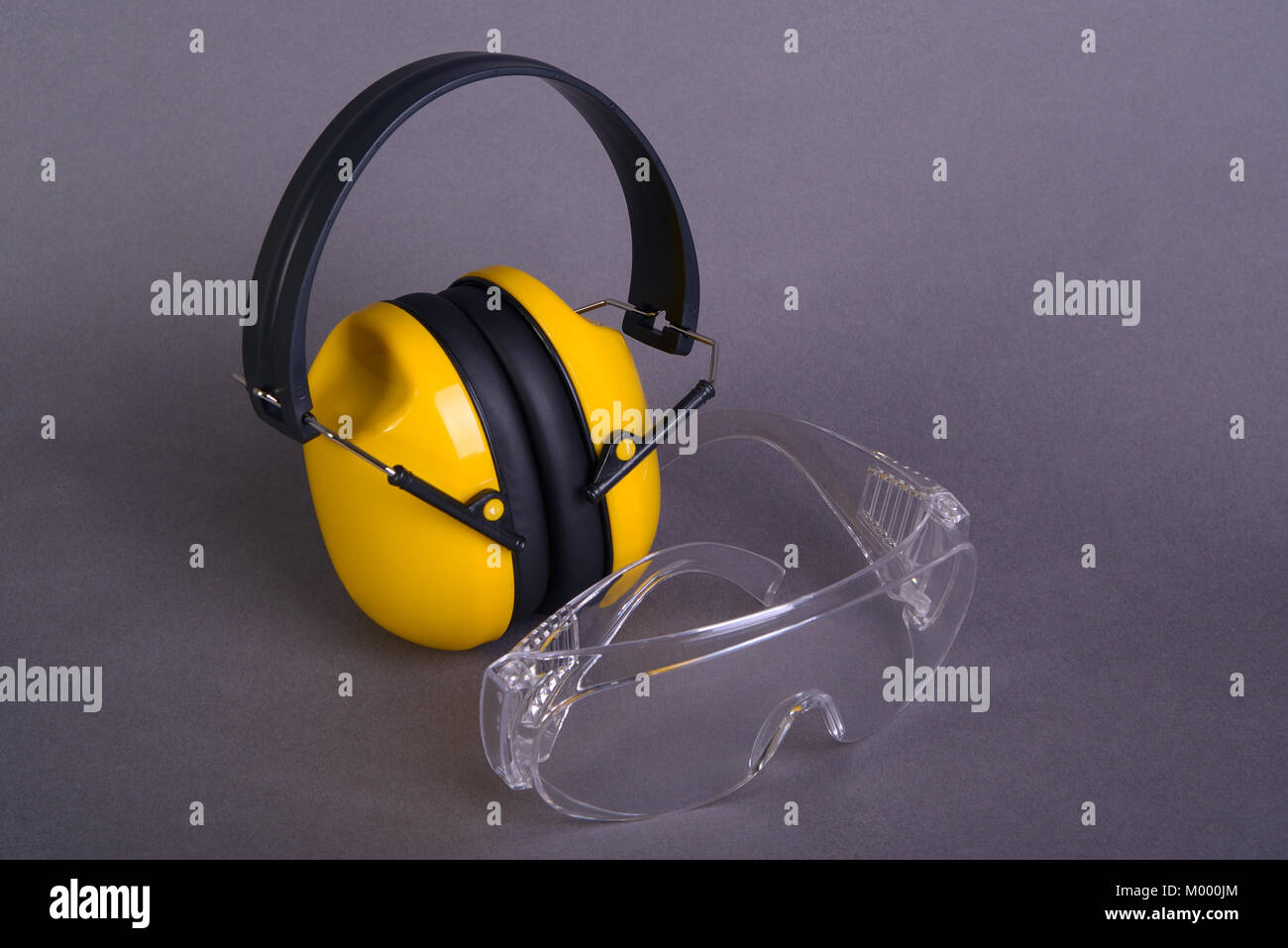 Safety glasses and yellow ear muffs on gray background Stock Photo - Alamy