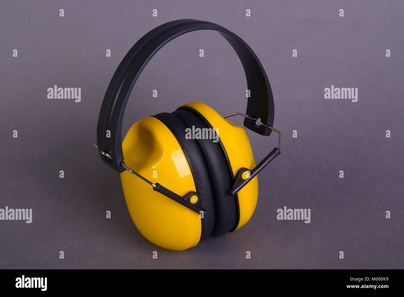 Yellow ear muffs on gray background Stock Photo - Alamy