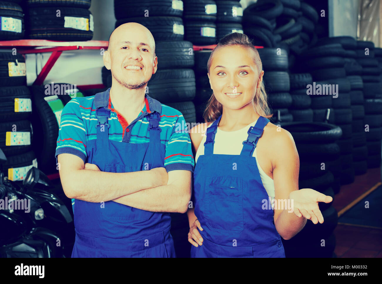 two cheerful smiling mechanics standing together in car repairing ...