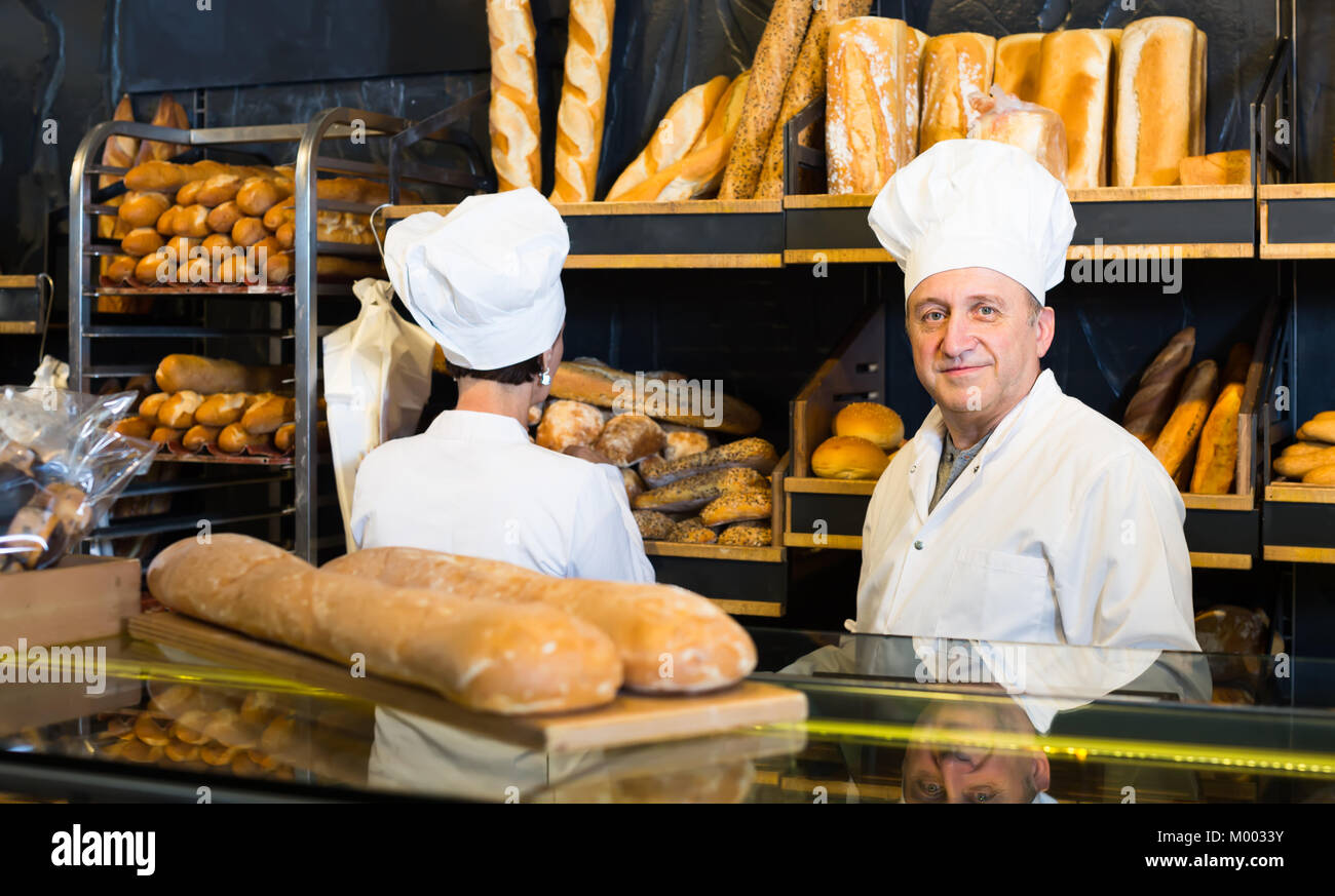 Portrait of attentive bakers with fresh bread smiling in bakery Stock ...
