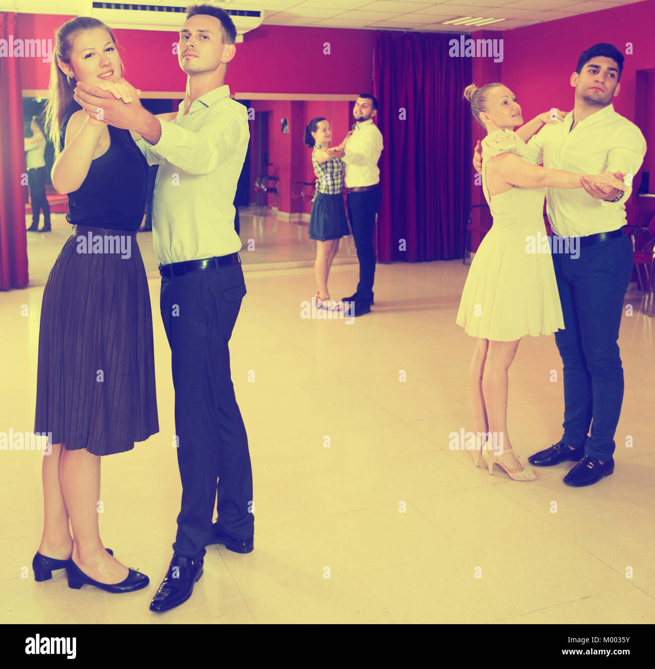 Young positive people dancing together slow ballroom dances in pairs ...