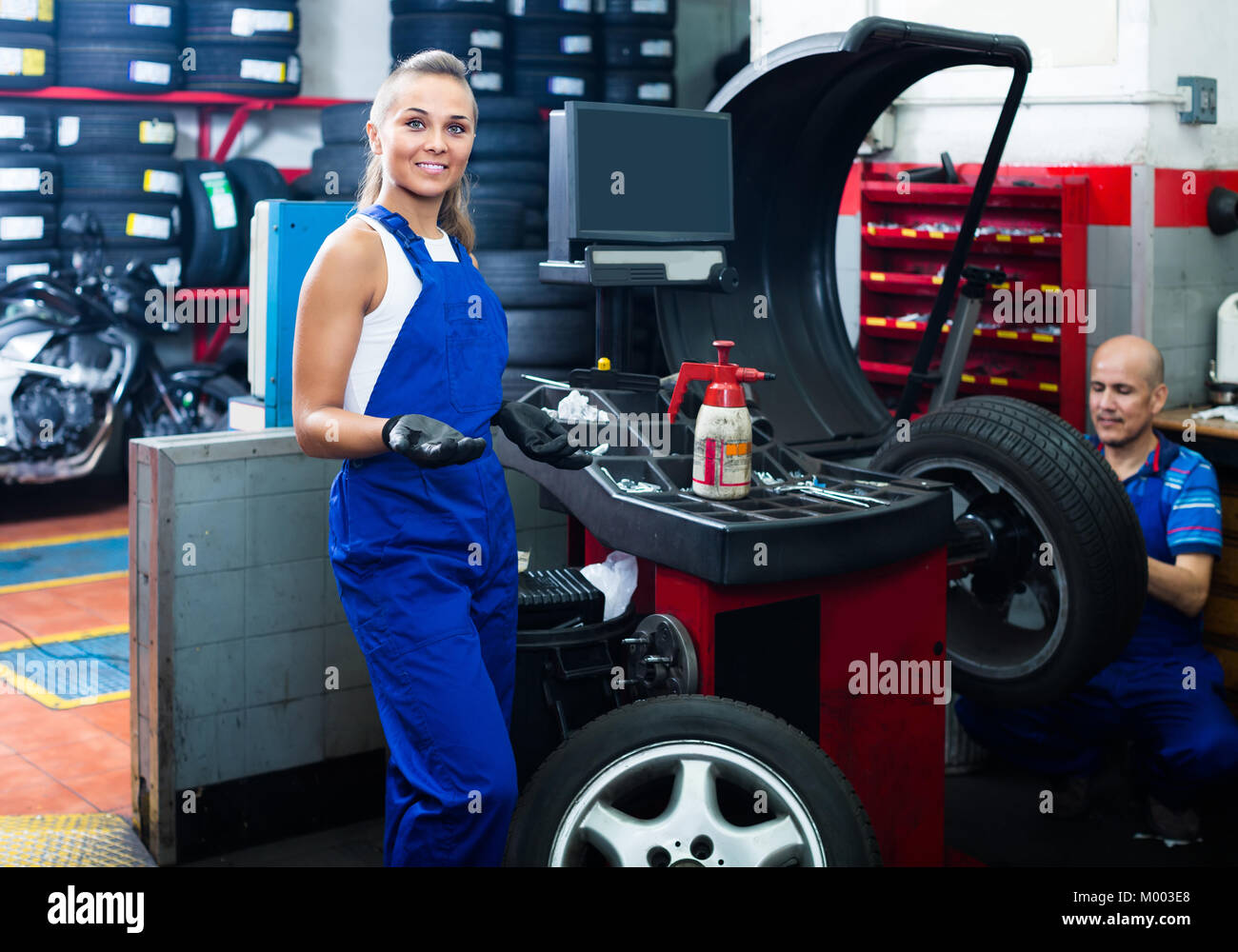 Young russian female technician standing with wheel balancing machinery ...