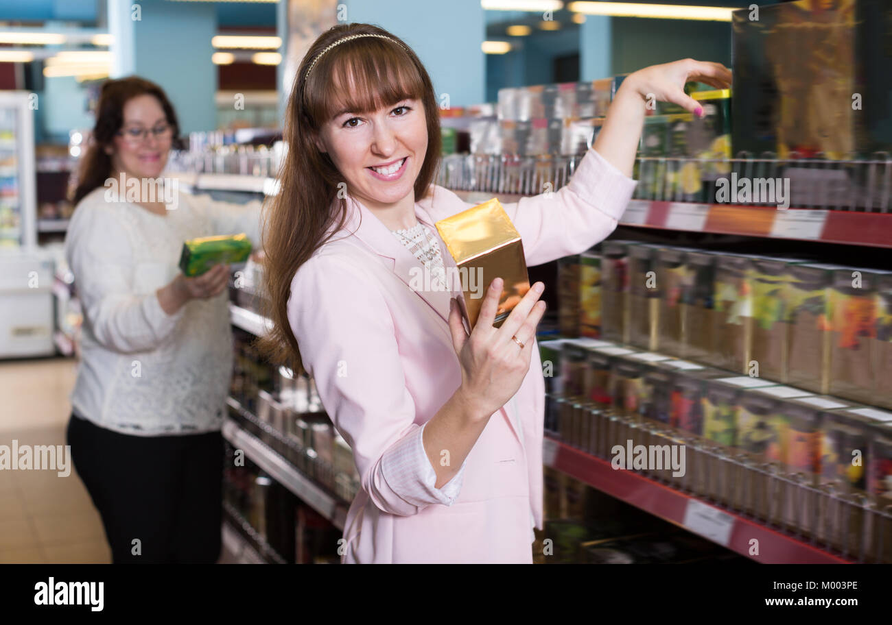 Smiling female buyers choosing tea on grocery shelves Stock Photo - Alamy