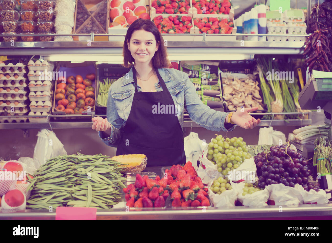 smiling female shopping assistant demonstrating assortment of grocery ...