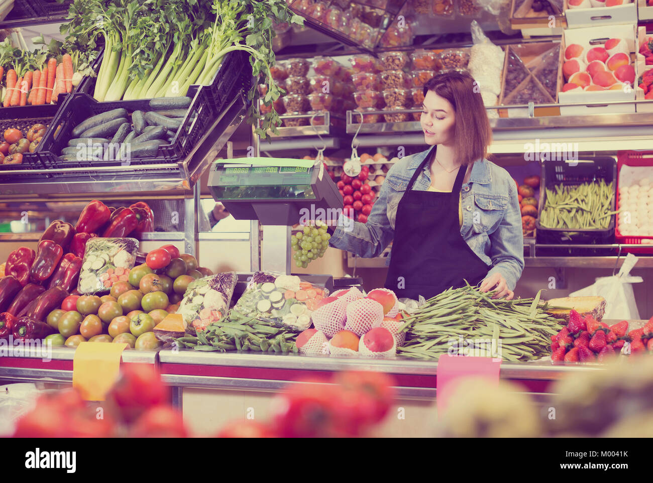 Young russian shopping assistant weighing fruit and vegetables in ...
