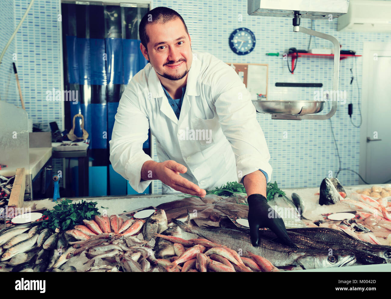 Seller shows hands fish on counter in supermarket Stock Photo - Alamy