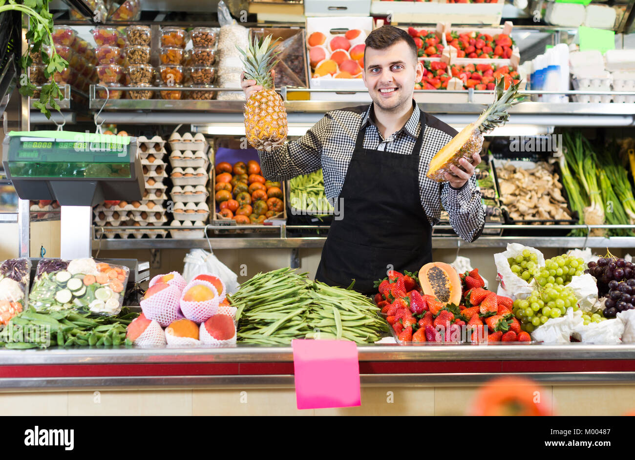 Guy shop assistant is displaying assortment of grocery shop Stock Photo ...