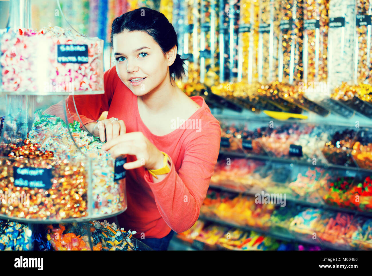 Happy brunette girl buying candies at shop Stock Photo - Alamy