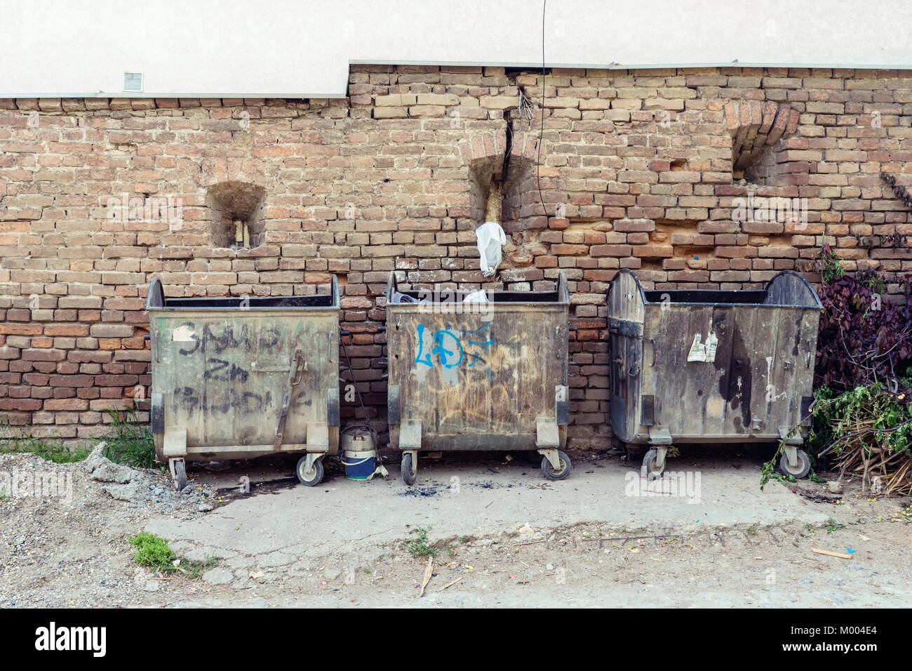 Tree old metal garbage containers in front of brick wall Stock Photo ...