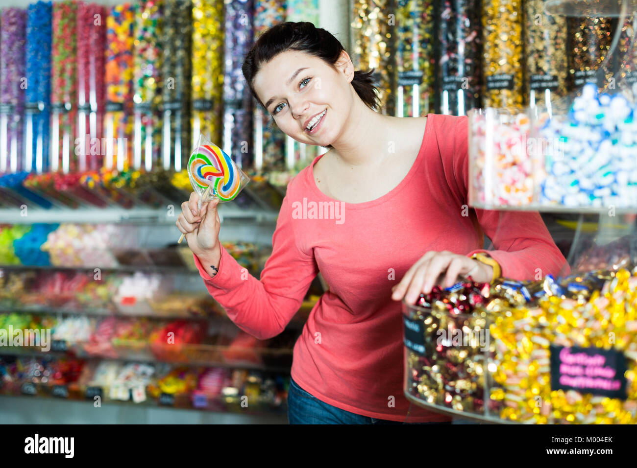 Happy brunette girl buying candies at shop Stock Photo - Alamy