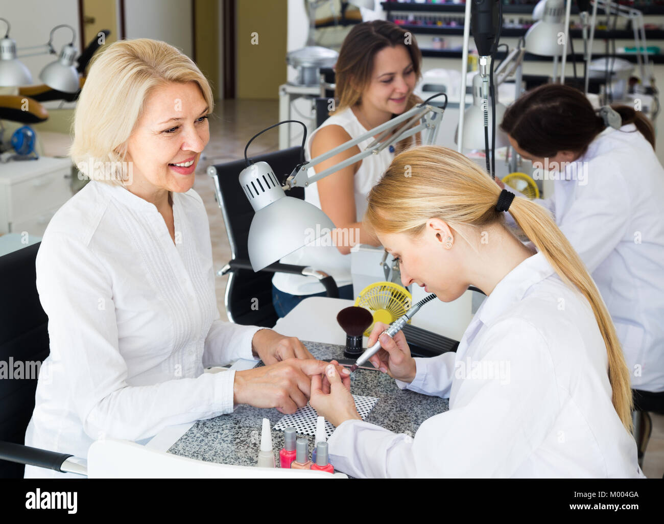 Two pretty women doing manicure in nail salon Stock Photo - Alamy