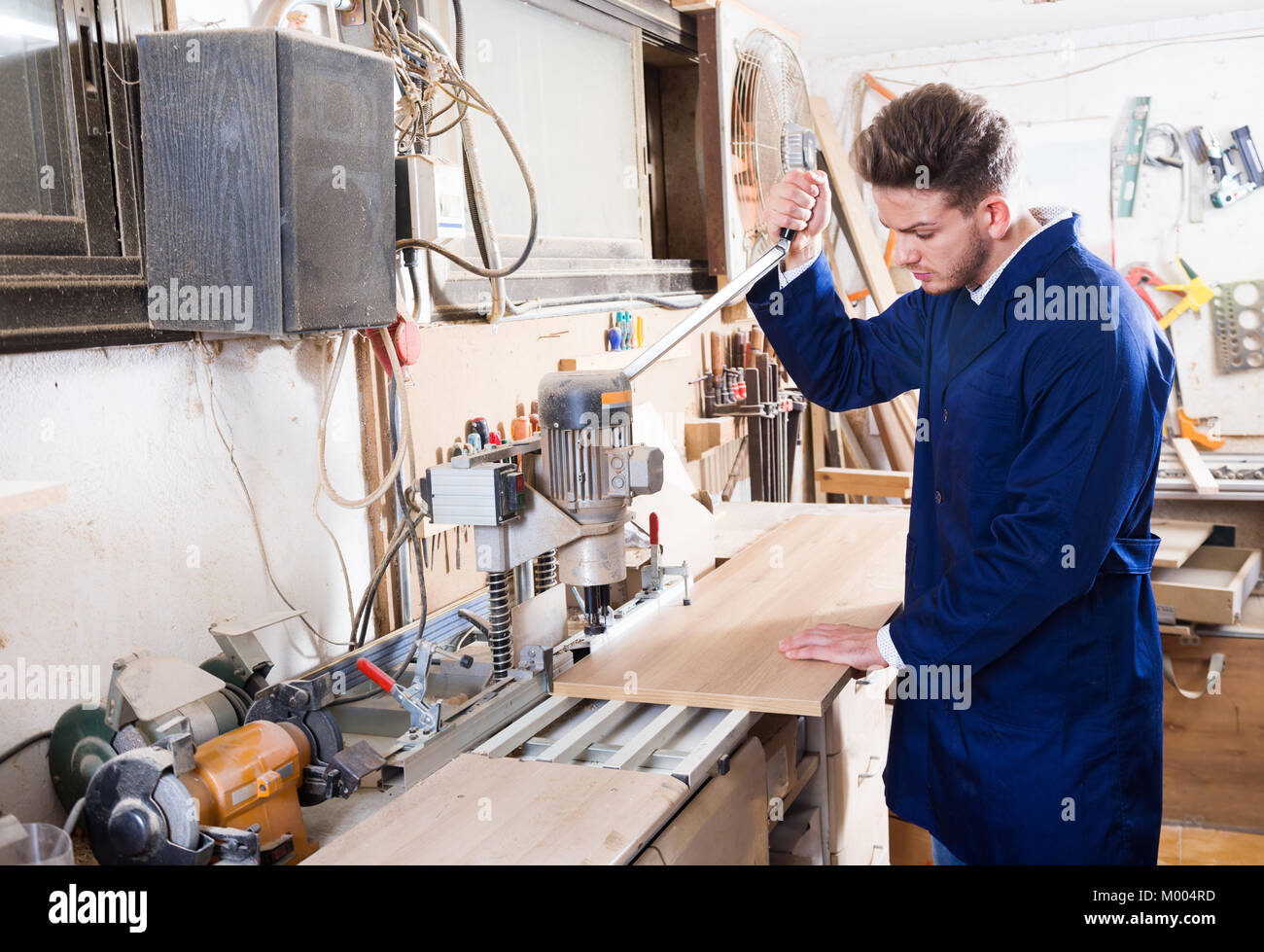 Smiling working man preparing a chipboard for work at a his workshop ...